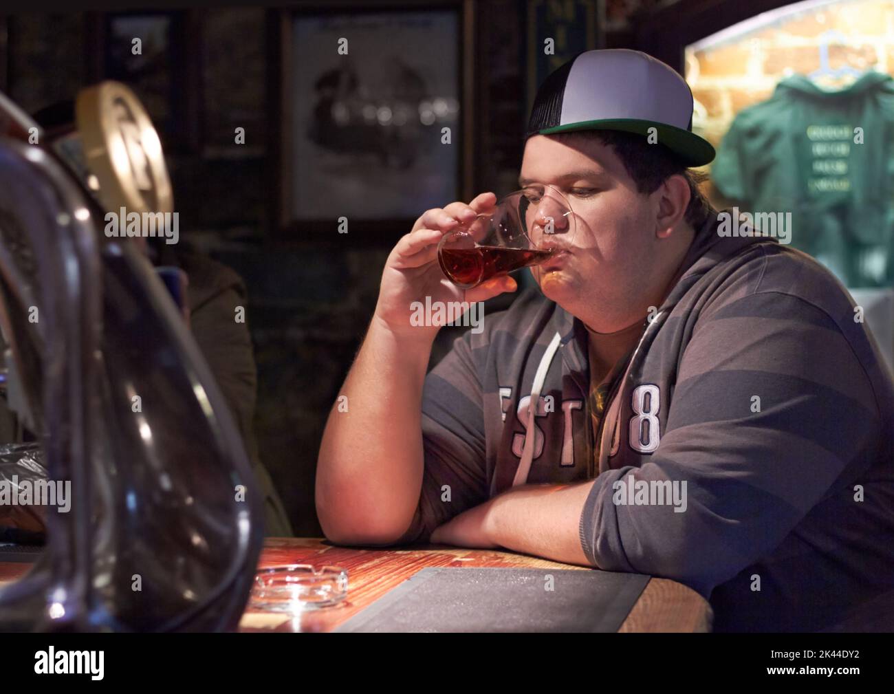 Washing the worries away. A young man drinking alone at the bar Stock ...