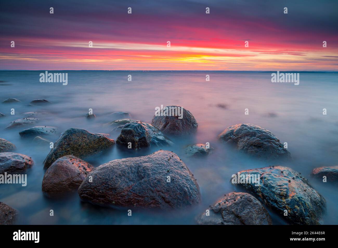 Colorful coastal autumn sunset with wet rocks and sea surf at ...