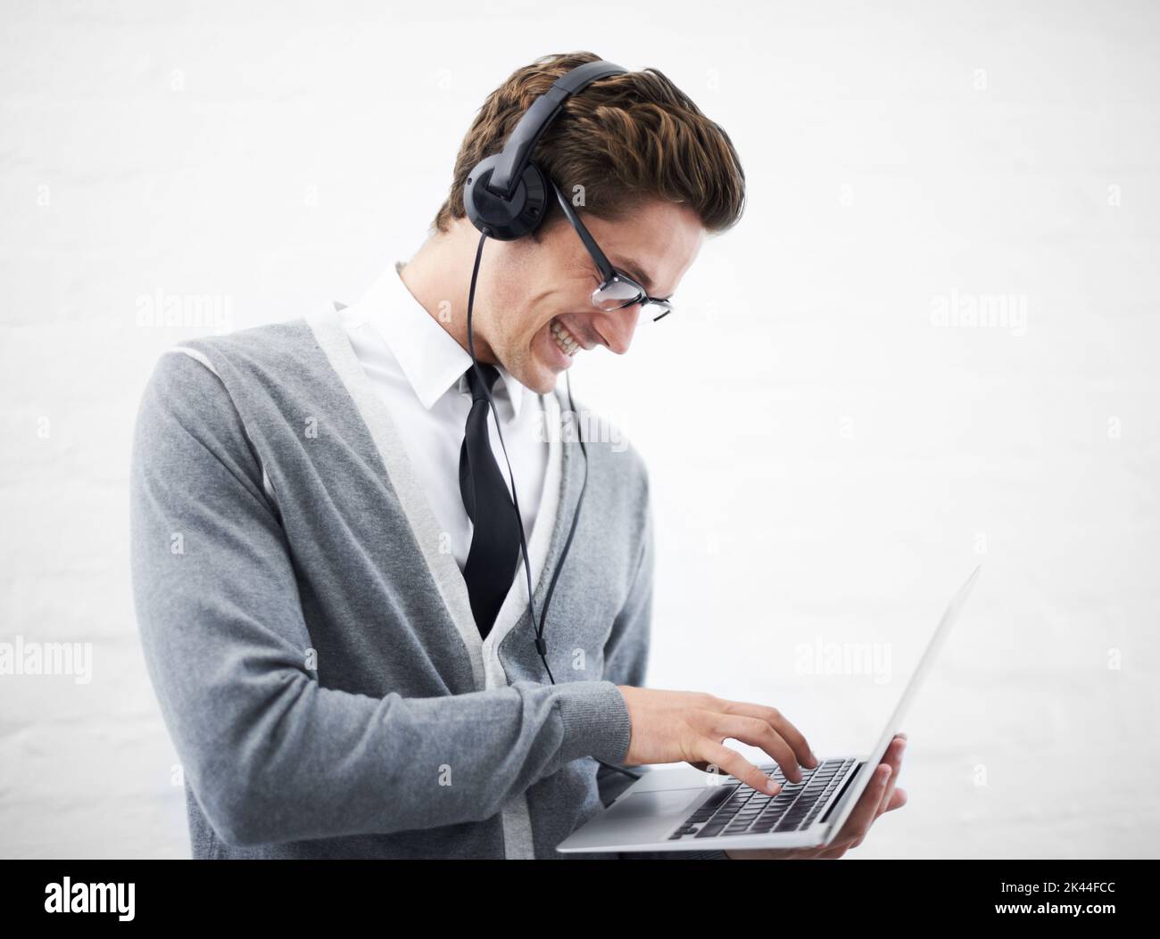 Managing his playlist. A handsome young nerd with headphones working on ...