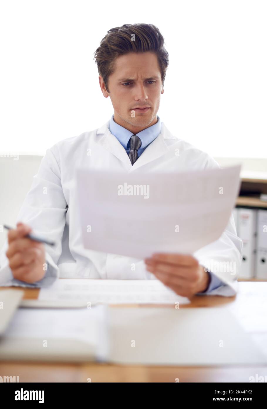 Going over the results again. a concerned young doctor sitting at his ...