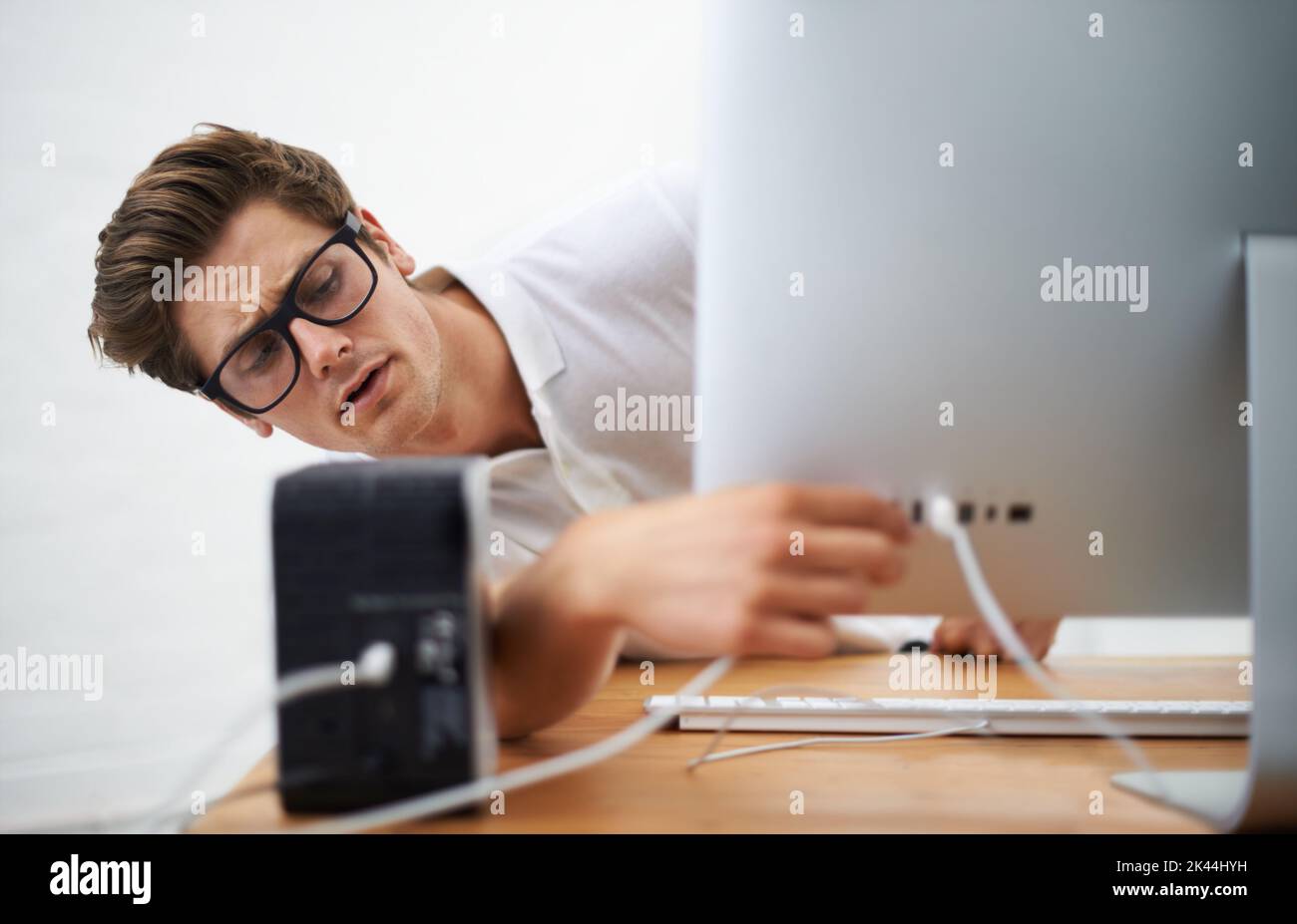 Ive got this. A young man trying to plug a cable into his computer ...