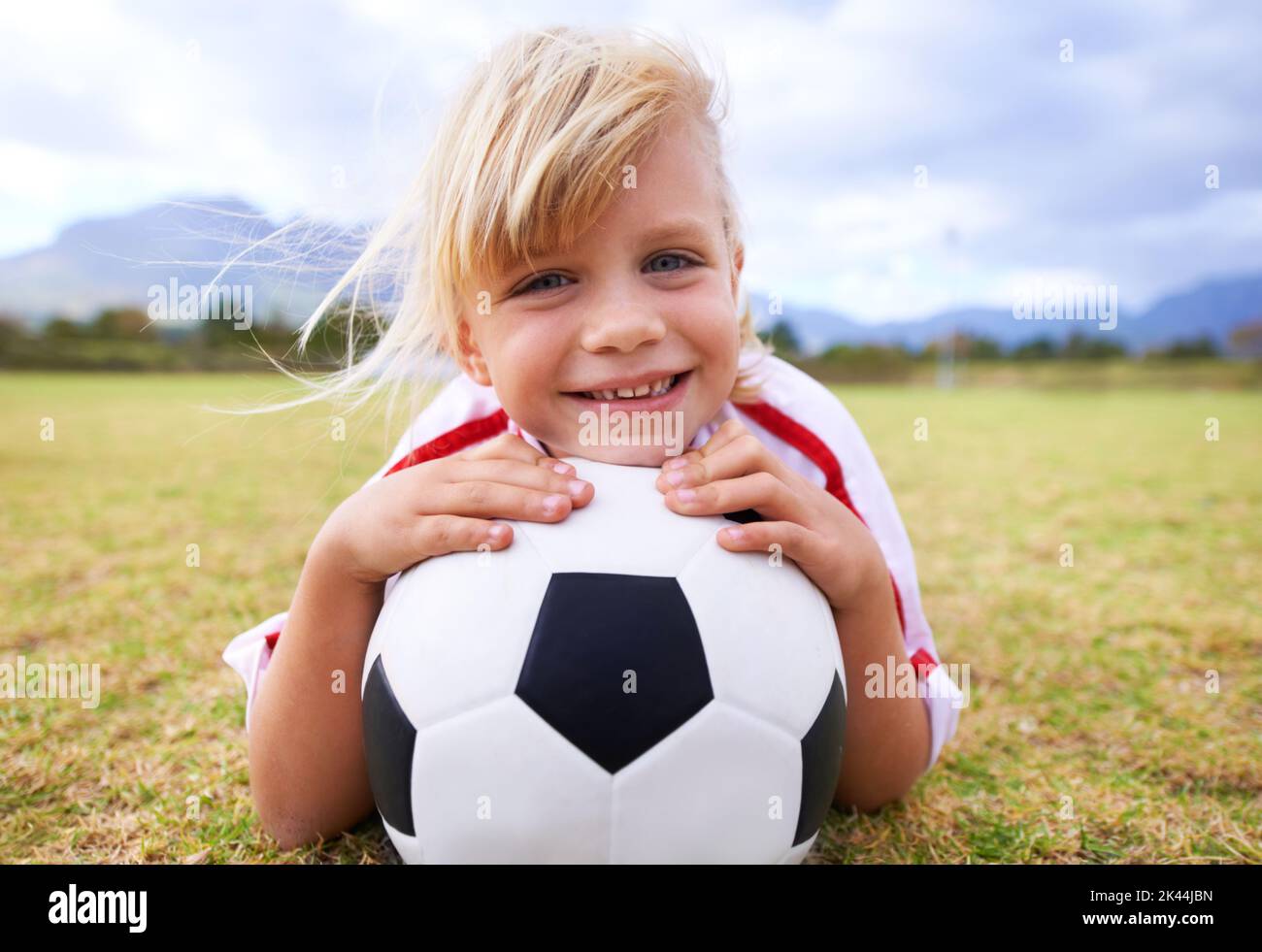 She loves the game. A young soccer player lying on the grass while ...