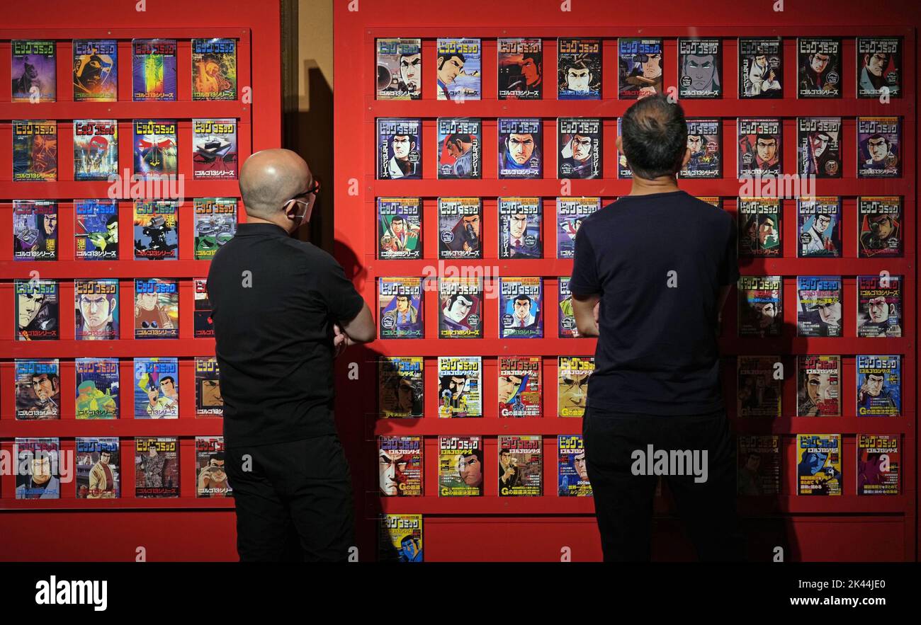 Two people look at magazine covers on display at a farewell gathering ...