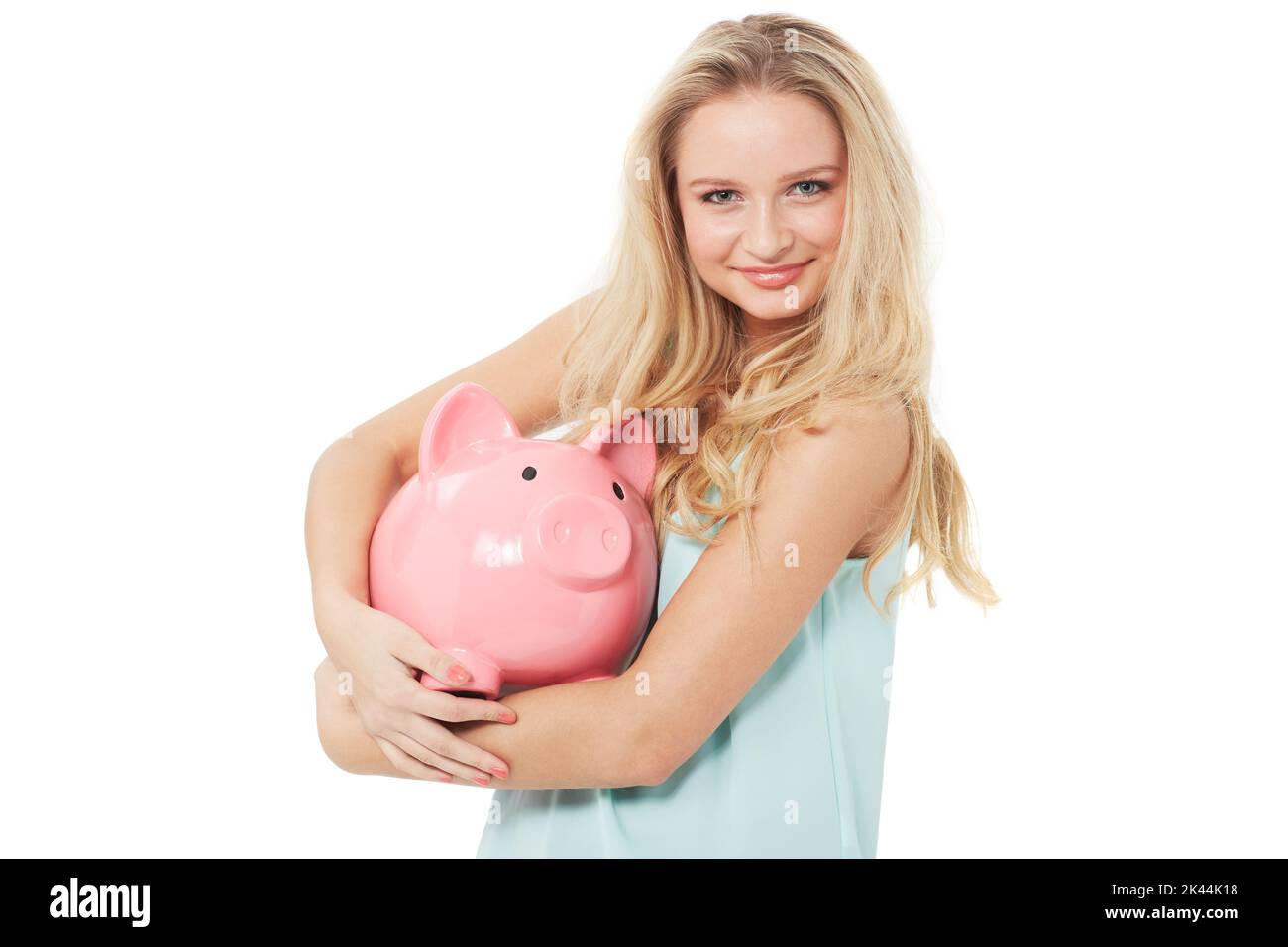 Taking care of her money. A pretty young woman hugging her piggy bank ...