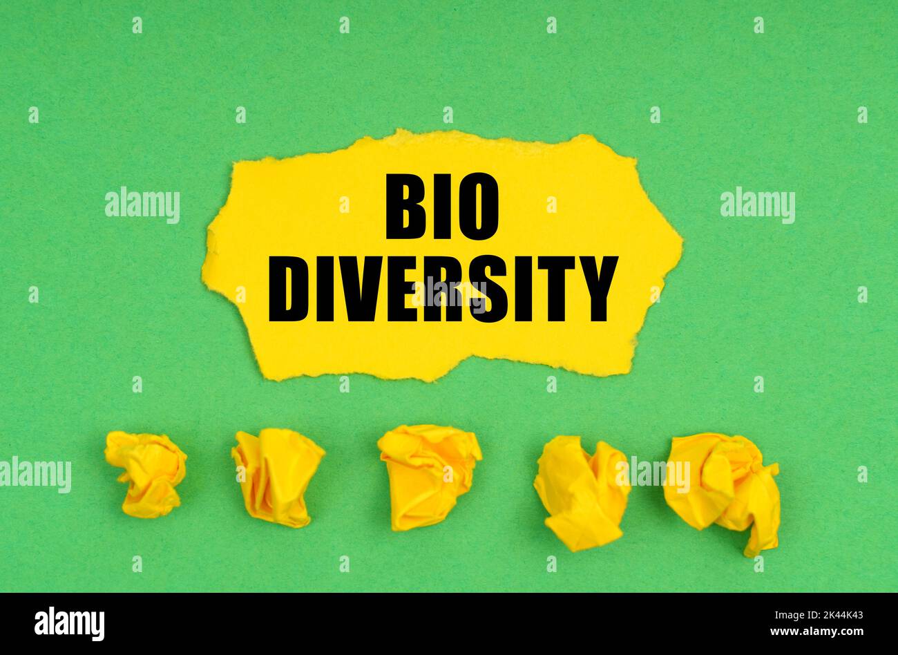 Ecology concept. On a green background, crumpled yellow paper and a ...