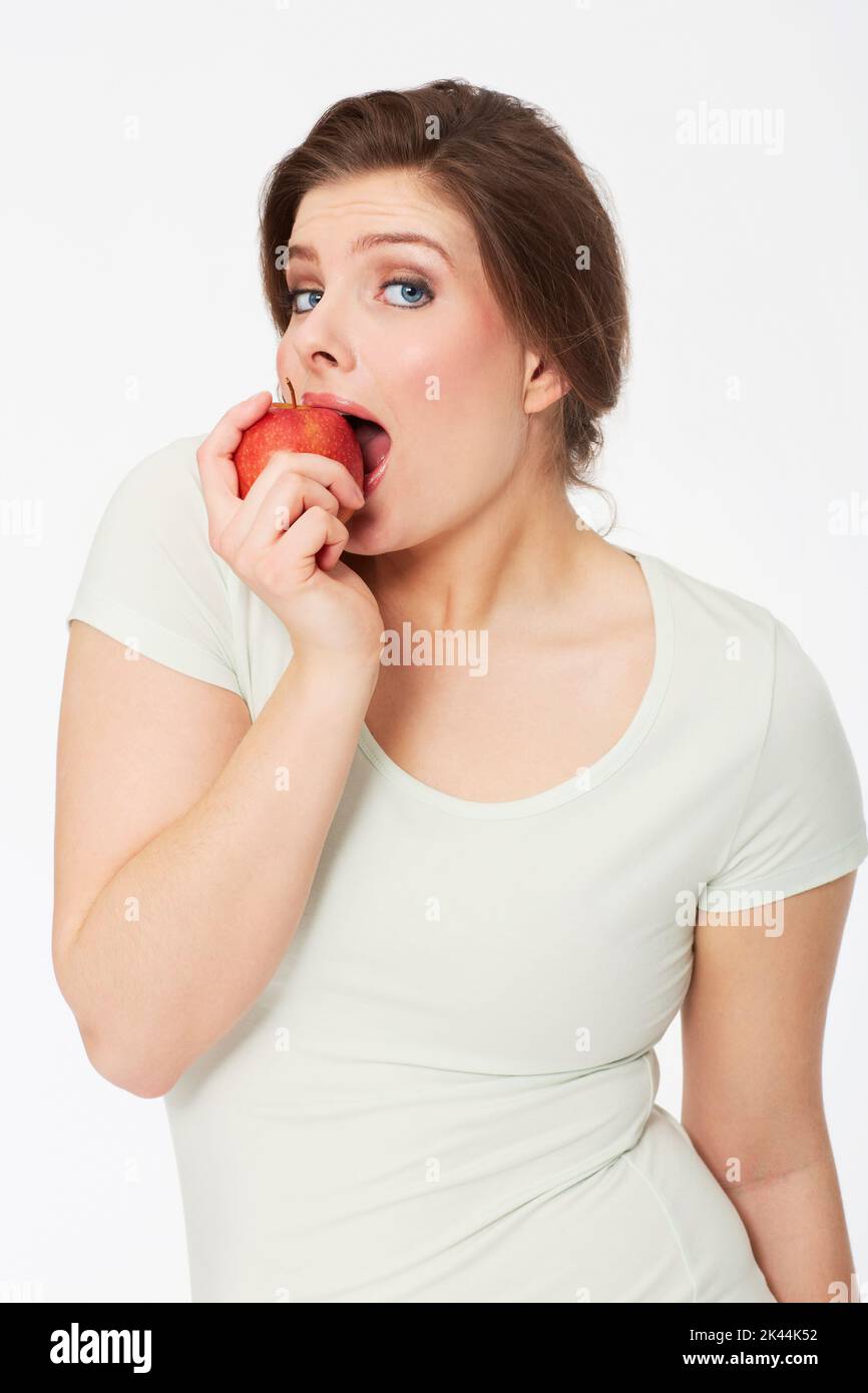 Delicious. Pretty brunette woman taking a bite out of an apple Stock ...