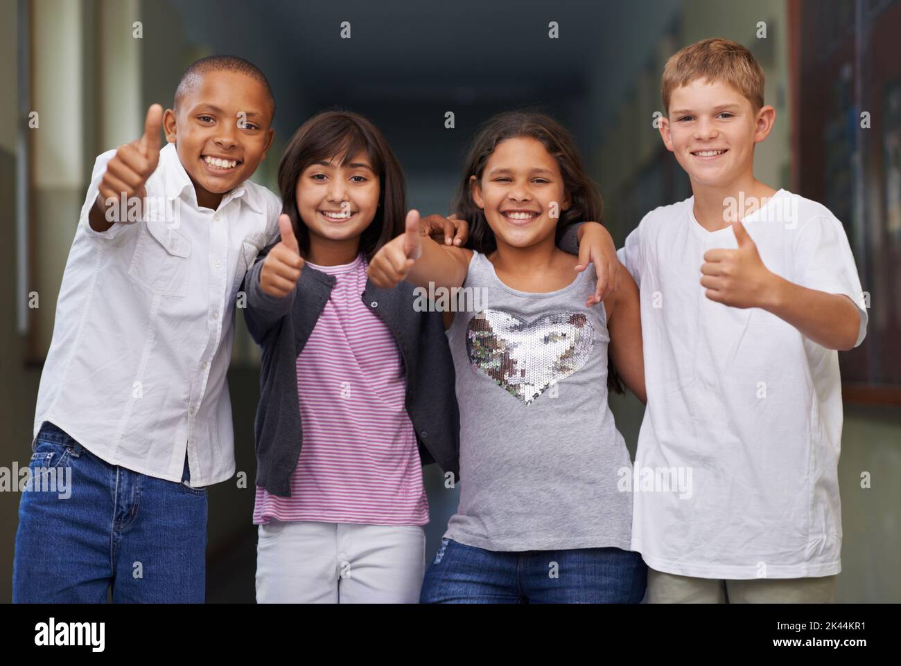 Friends make school fun. Four friends standing arm-in-arm and giving ...