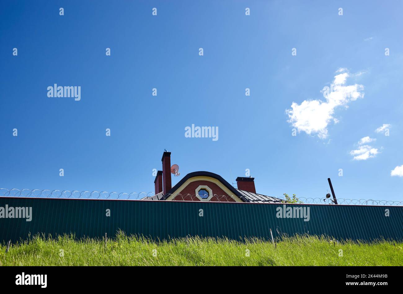 Facade of a European suburban building. Metal fence and house against a ...