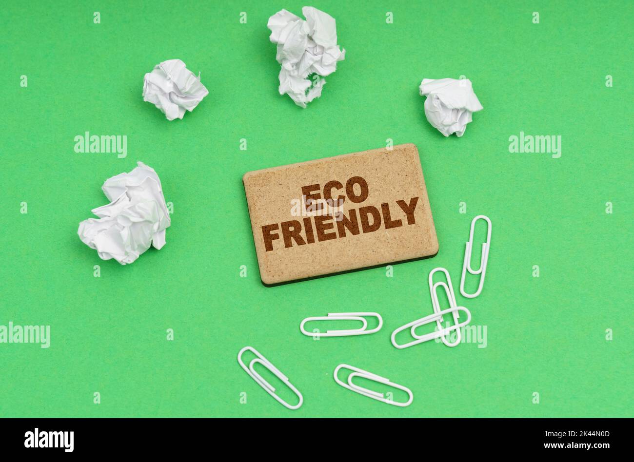 Ecology concept. On a green background, crumpled paper, paper clips and ...