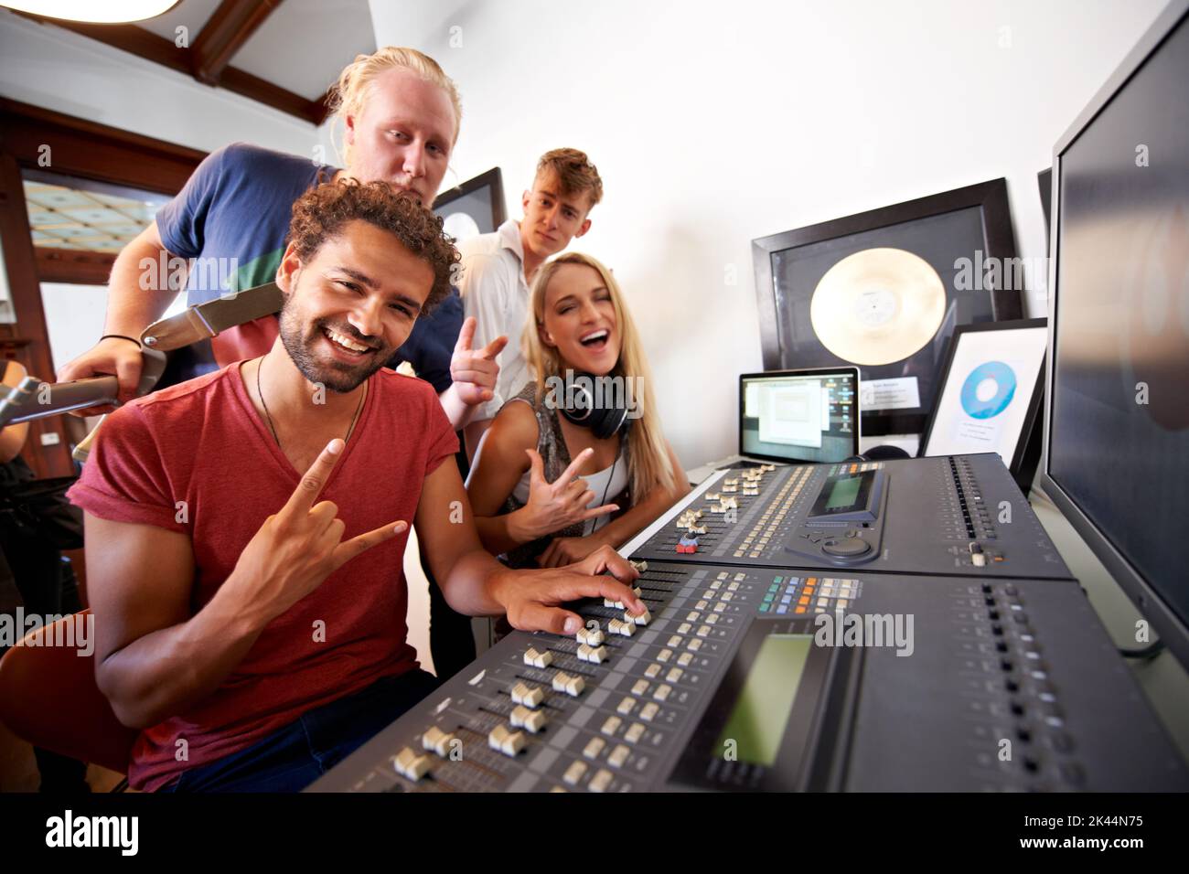 Hit Squad. Four young music producers sitting in front of a mixing desk ...