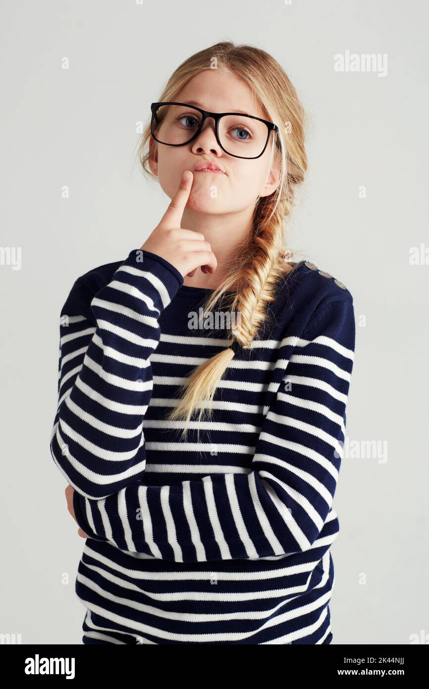 Mmm, what to do next...A cute girl looking thoughtful with her finger ...