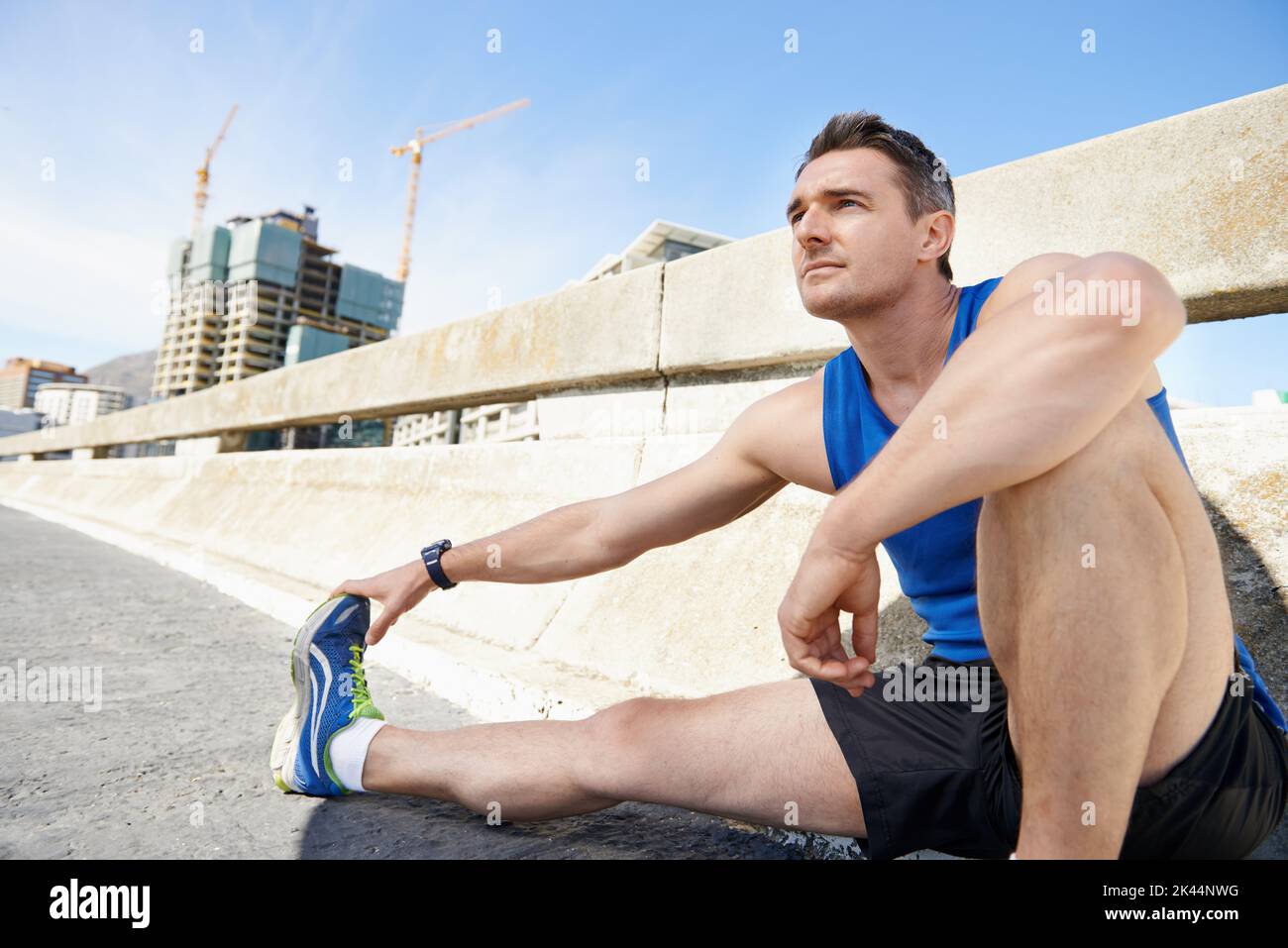 Stretching the hamstrings. A handsome man stretching his hamstrings ...
