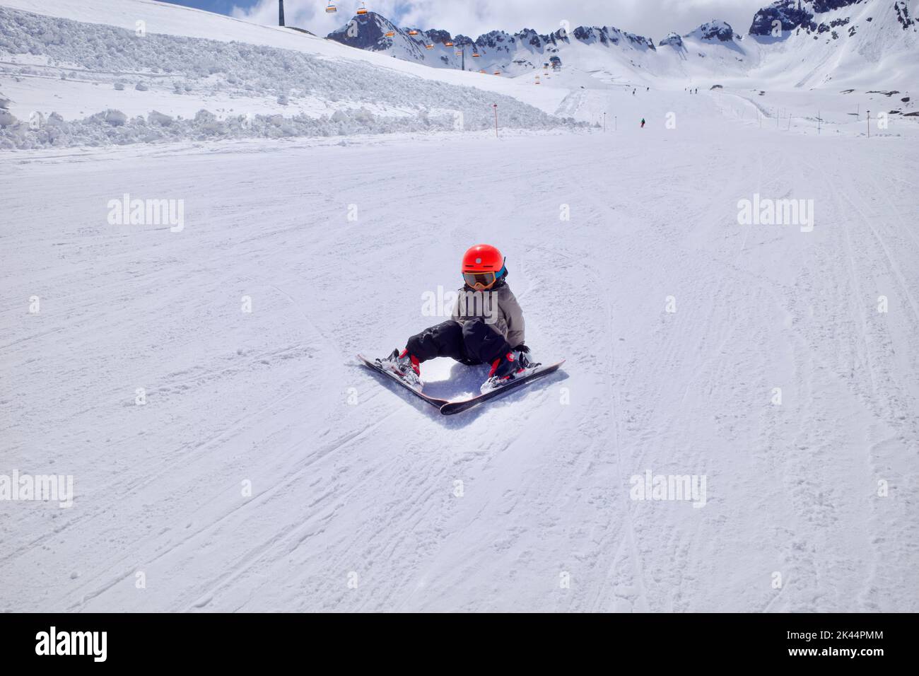 A kid sits on ski piste trying to get up Stock Photo - Alamy