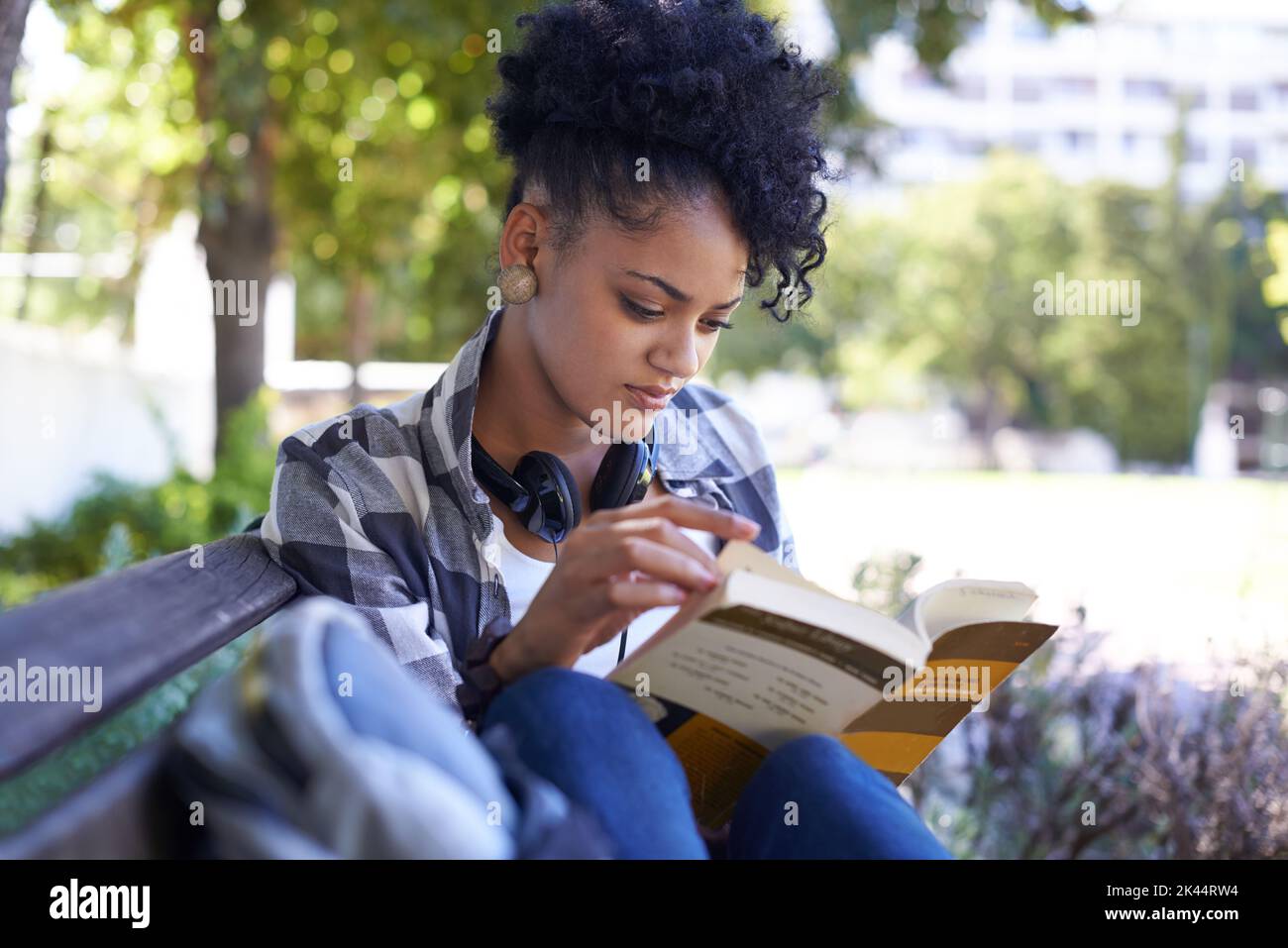 she wants to do well. A student sitting on a bench reading a book Stock ...