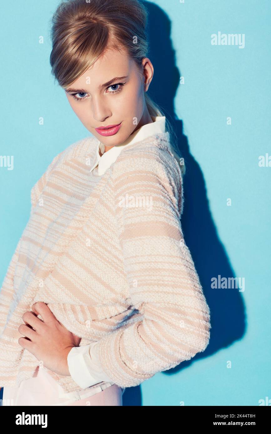 Vintage vixen. A lovely young fashionable woman posing against a blue background with her hand ...