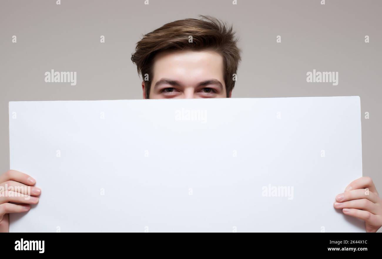 Young man with an empty sheet of paper half covering face stock photo ...
