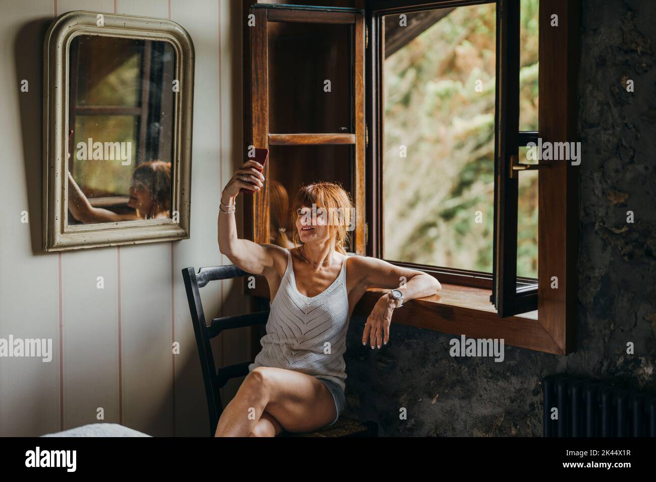 red-haired woman taking a selfie in a window Stock Photo - Alamy