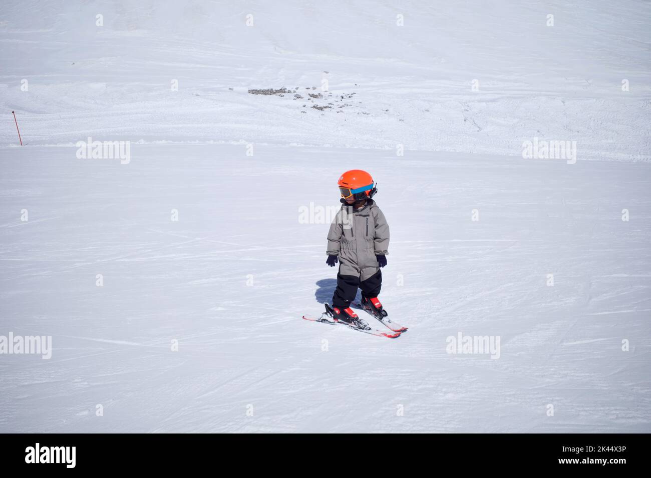 A kid skiing alone on the slope. He was standing and waiting for the ...