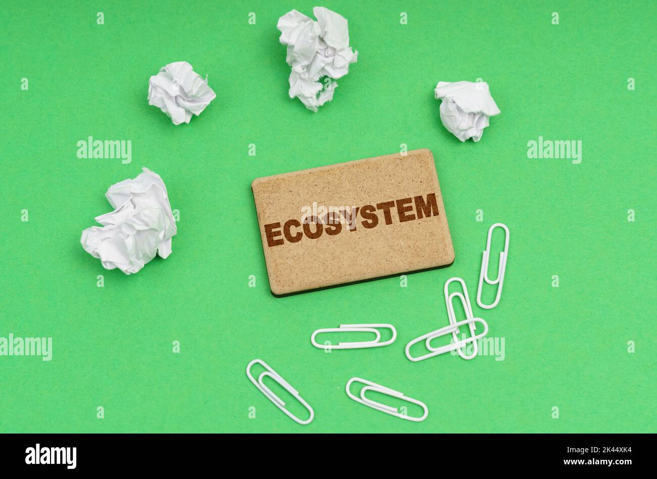 Ecology concept. On a green background, crumpled paper, paper clips and ...