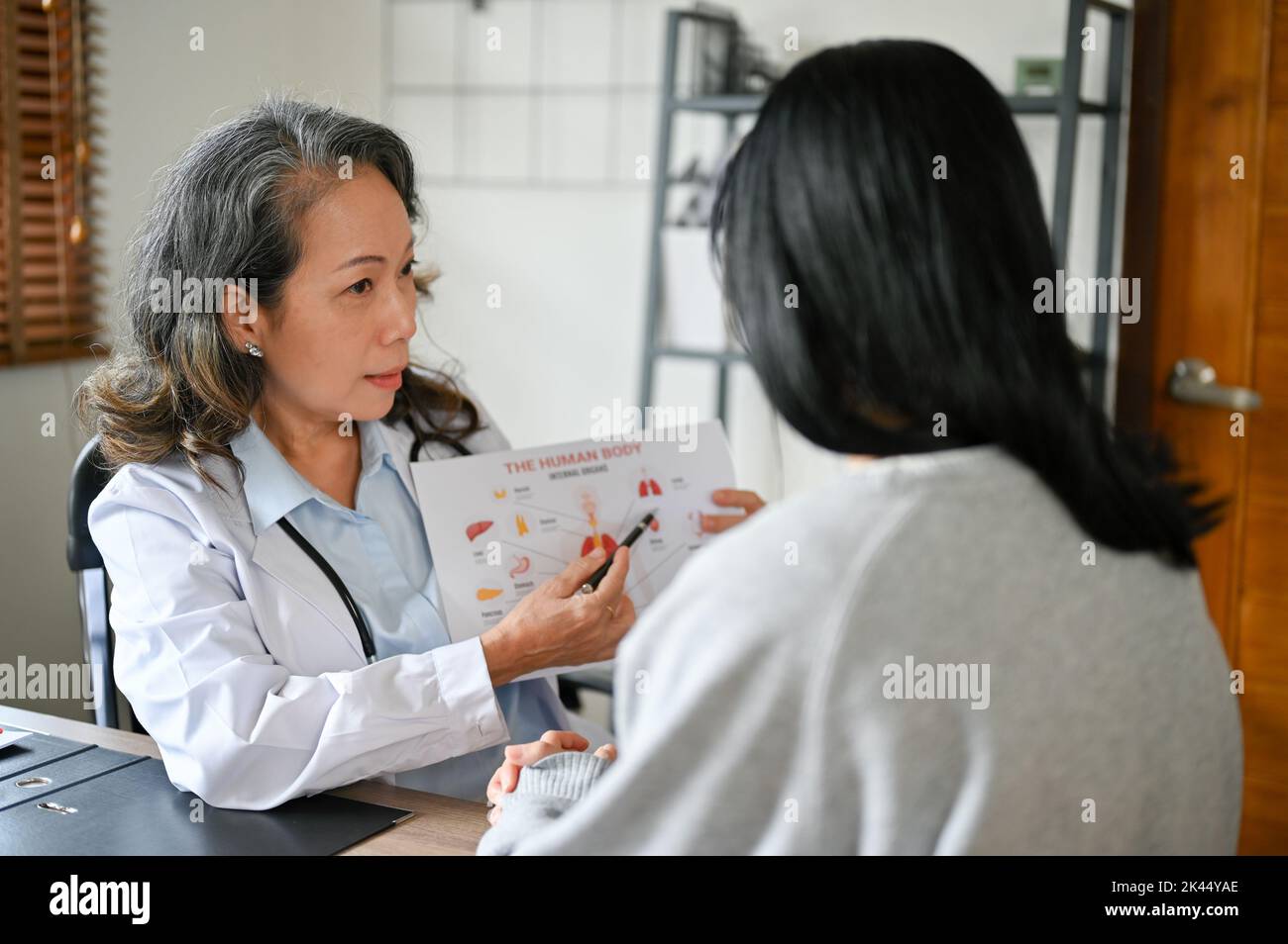 Professional senior Asian female doctor explaining a human body system ...