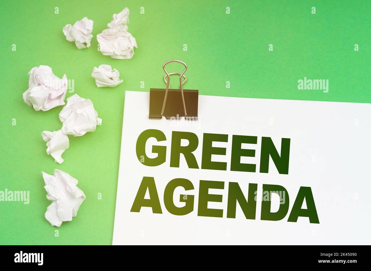 Ecology concept. On a green background, crumpled paper and a sheet with ...