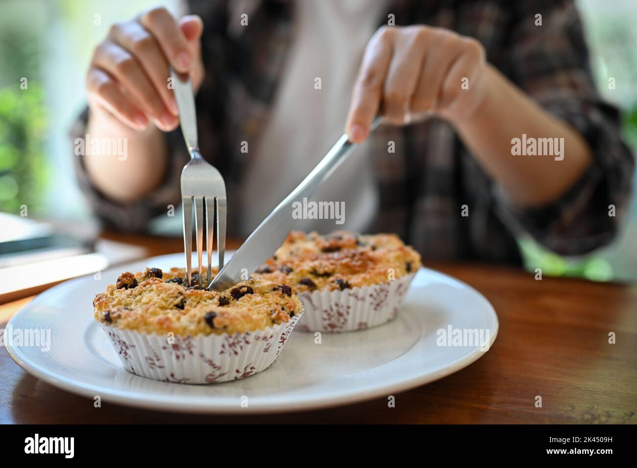 Young Asian female enjoys eating wholewheat muffin with raisins in the ...