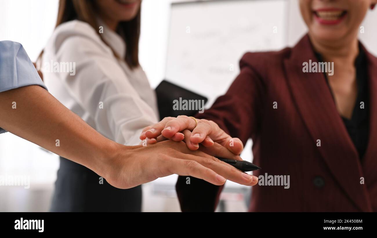 Close up image of successful businesspeople stacking hands together ...