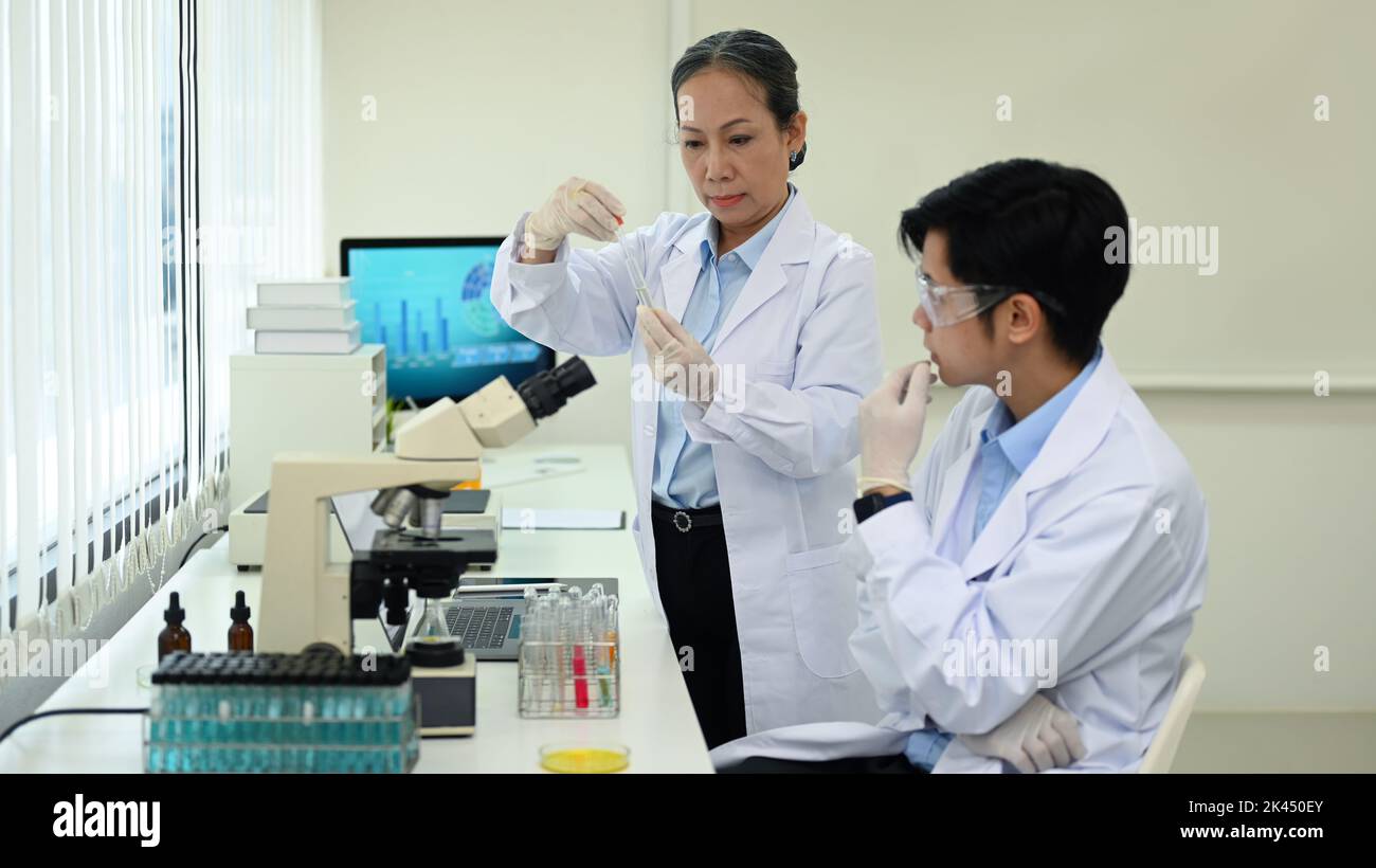 Two professional scientist conducting experiment with test tubes and ...