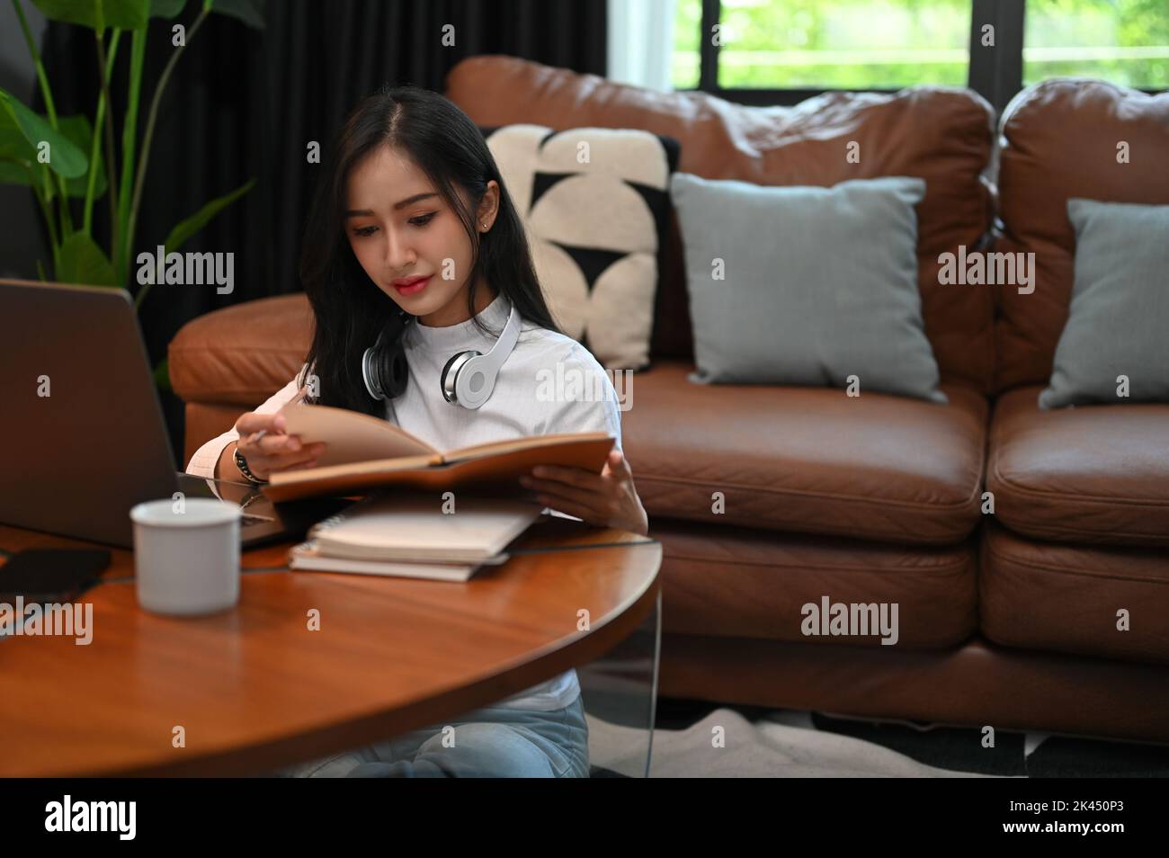 Smart young Asian female college student concentrating doing homework ...