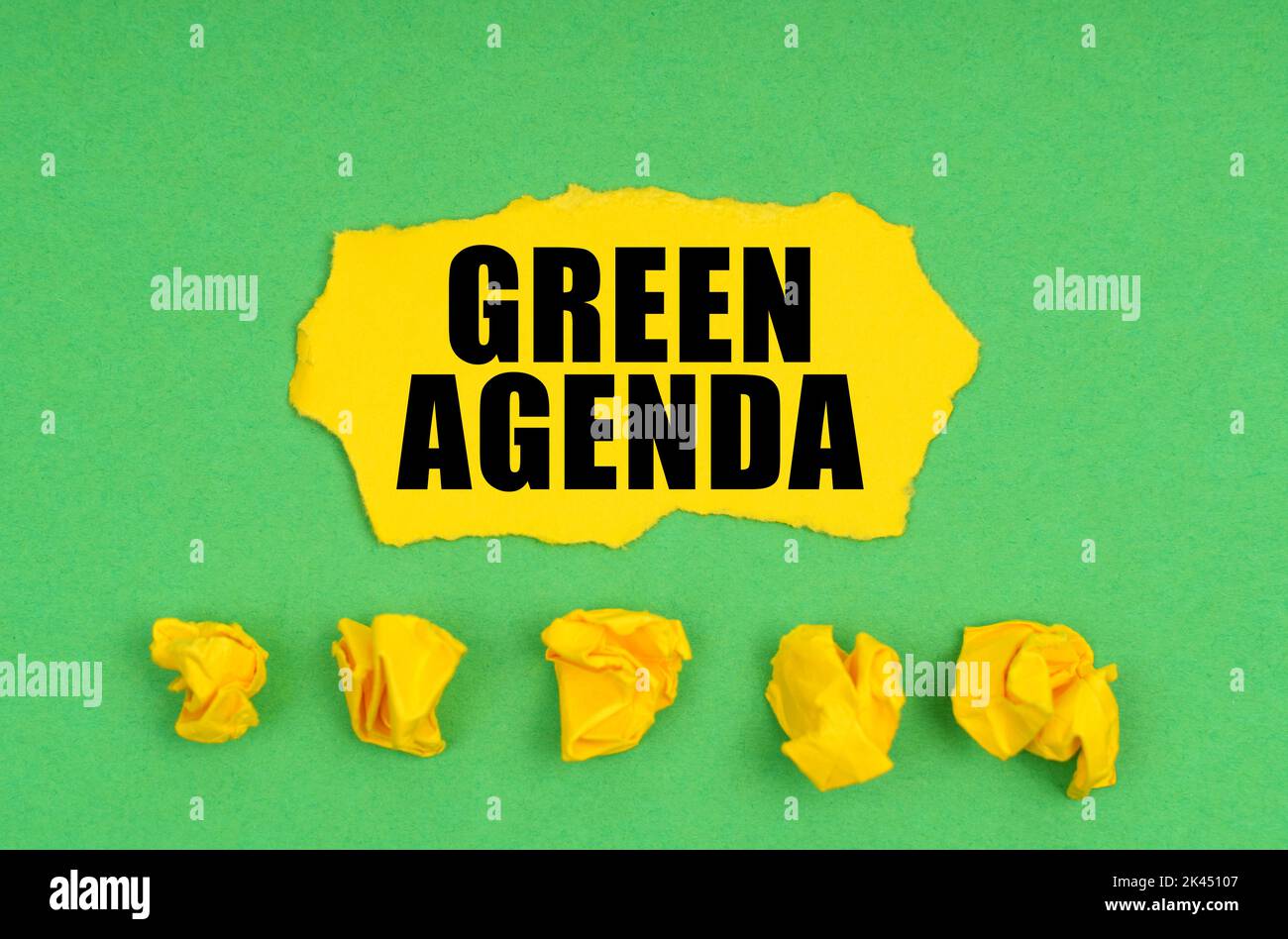 Ecology concept. On a green background, crumpled yellow paper and a ...