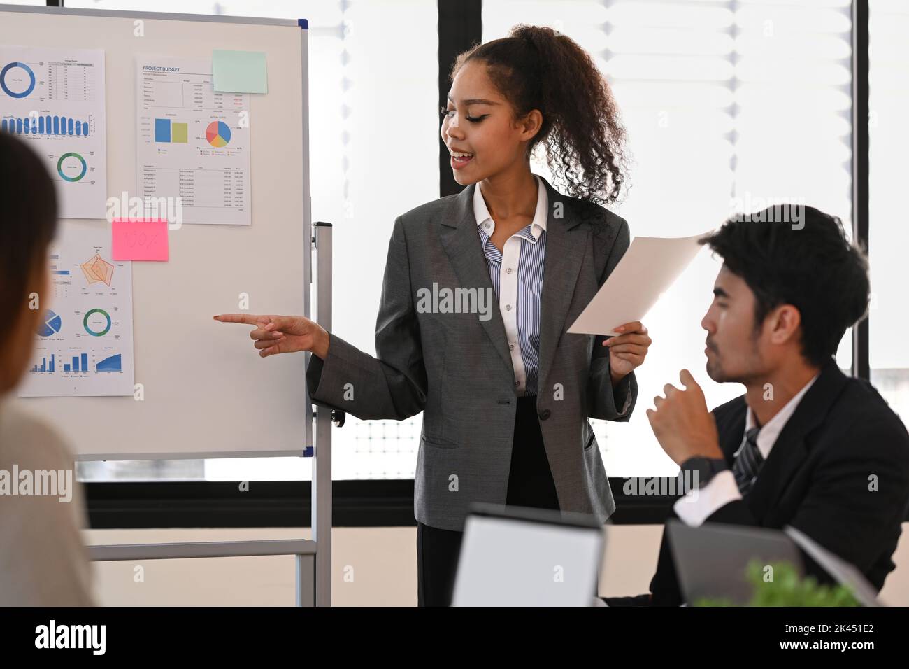 Confident female project leader giving business presentation ...
