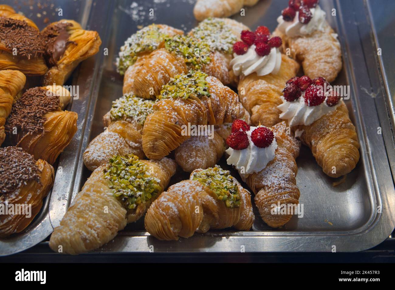 A bakery stand of pastry including Italian croissants with white cream ...