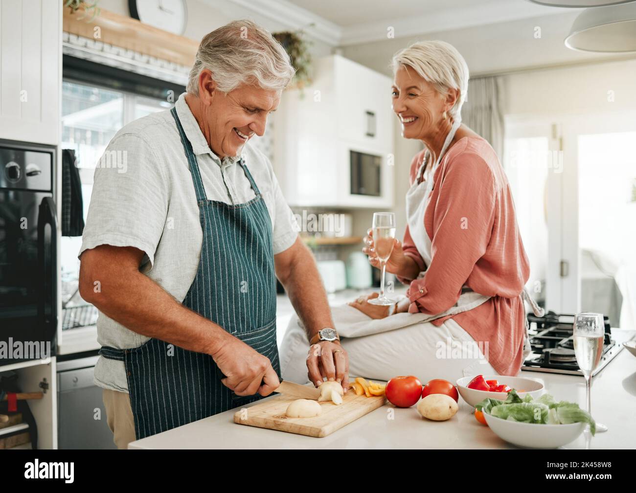 A happy senior couple, cooking healthy food in kitchen and drinking ...
