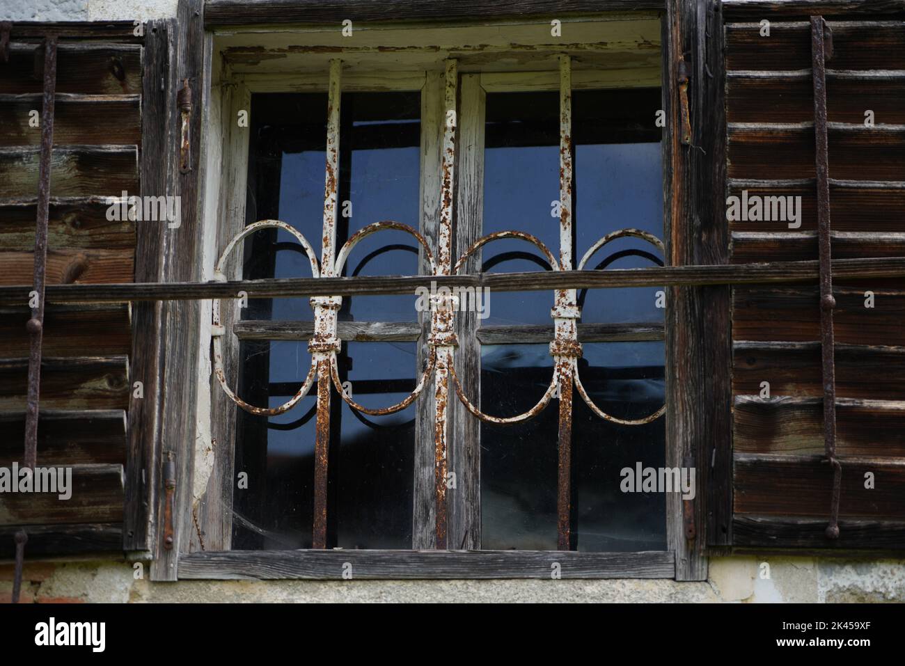 A closeup of an old window with wooden frames and rusty metal fence ...