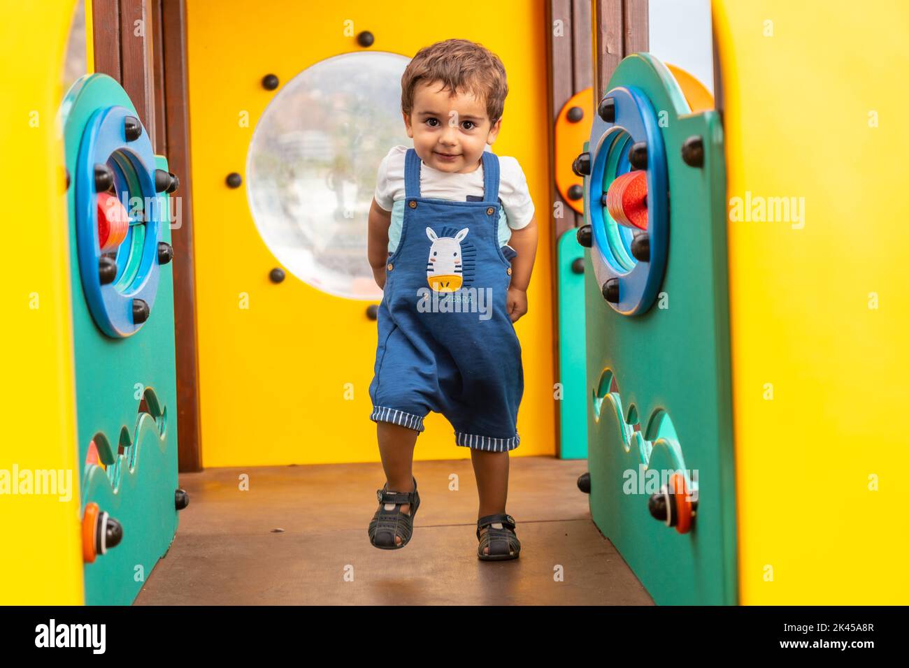 A little boy having fun and running around on colorful playground ...