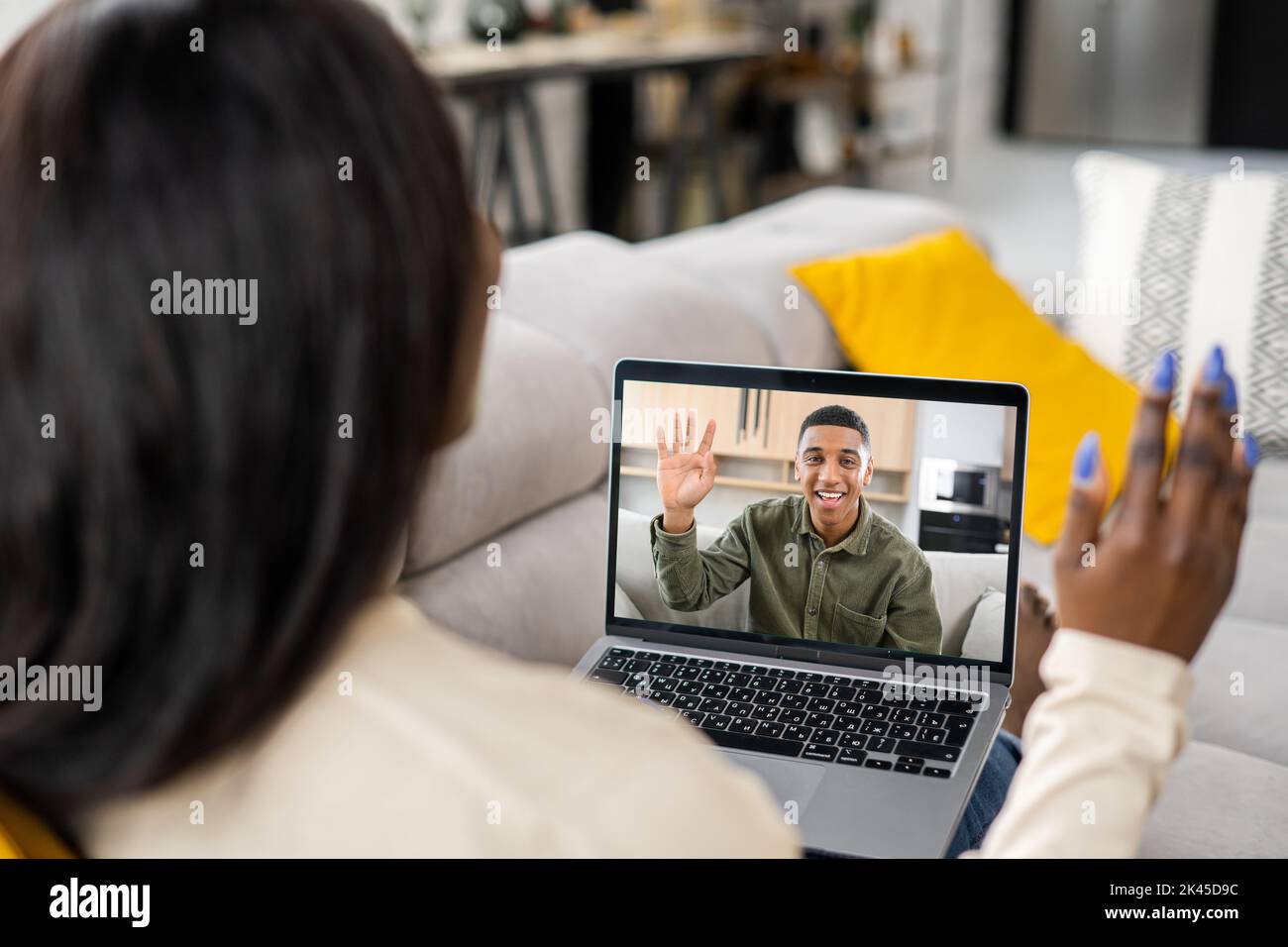 African woman using laptop for video connection with male friend or ...