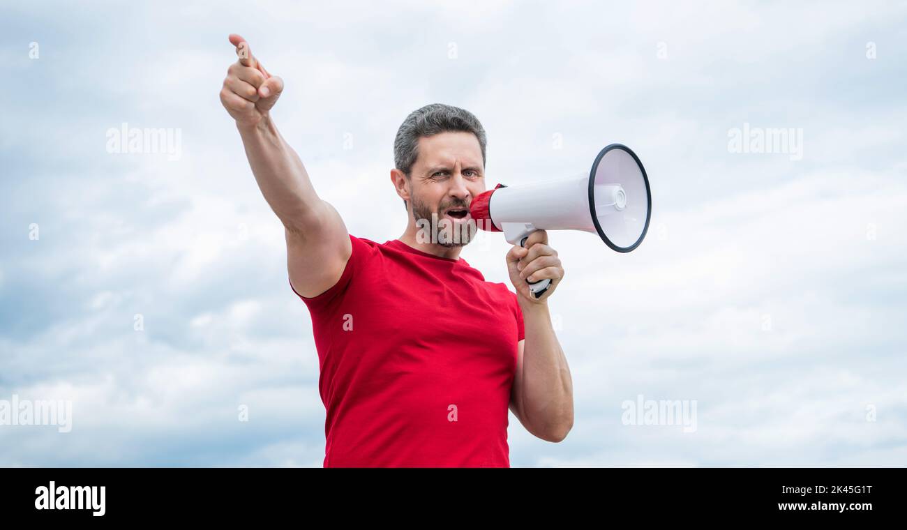 man in red shirt shout in loudspeaker on sky background. agitation ...