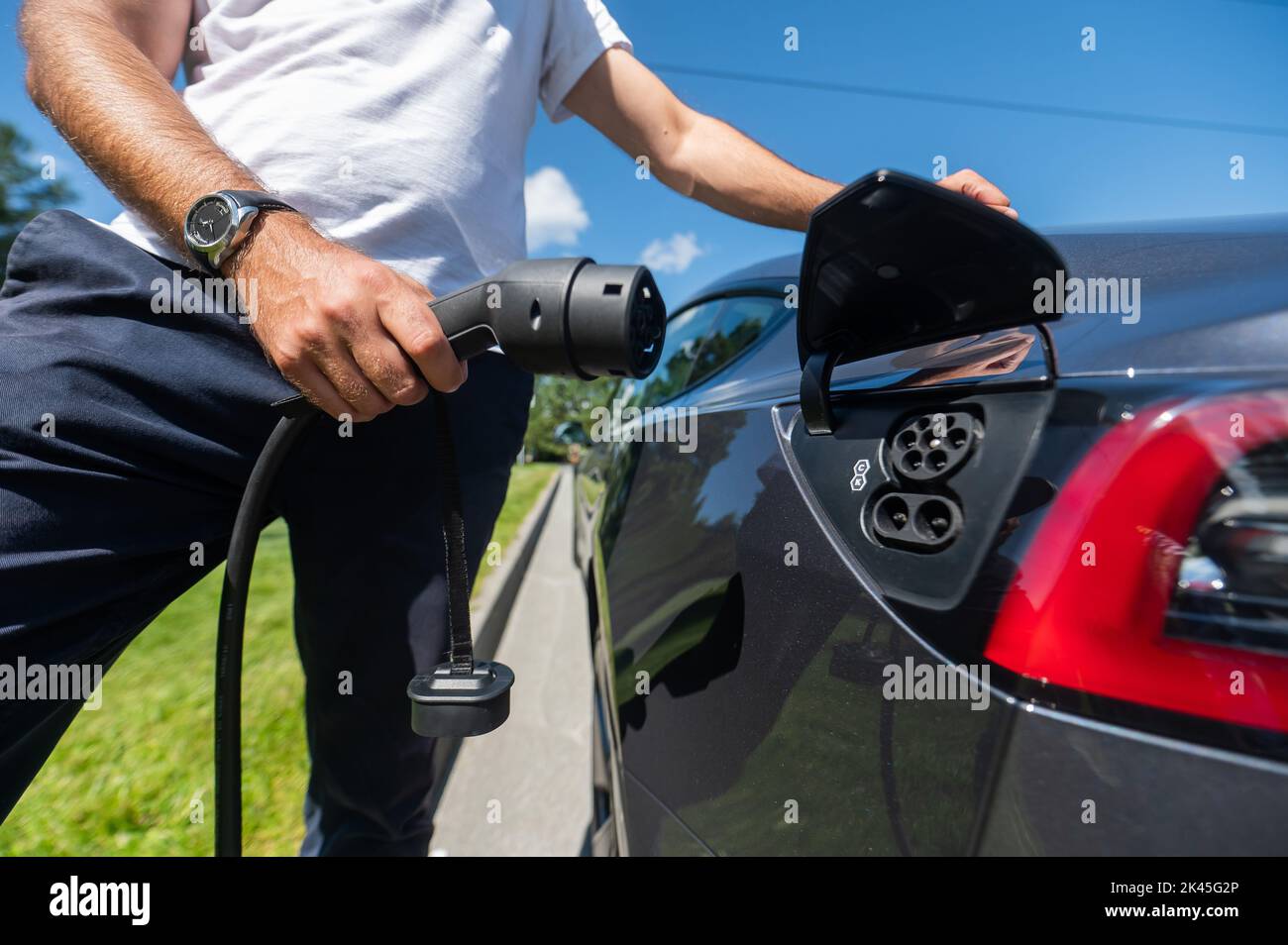Caucasian man connect charger to electric car Stock Photo - Alamy