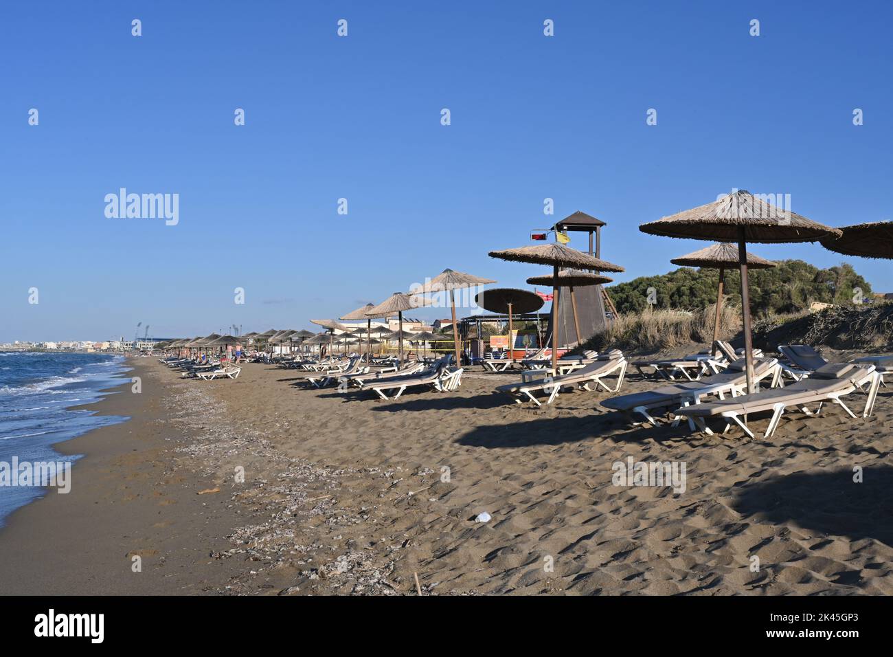 Sandy beach of a holiday resort with plastic deck chairs and straw ...
