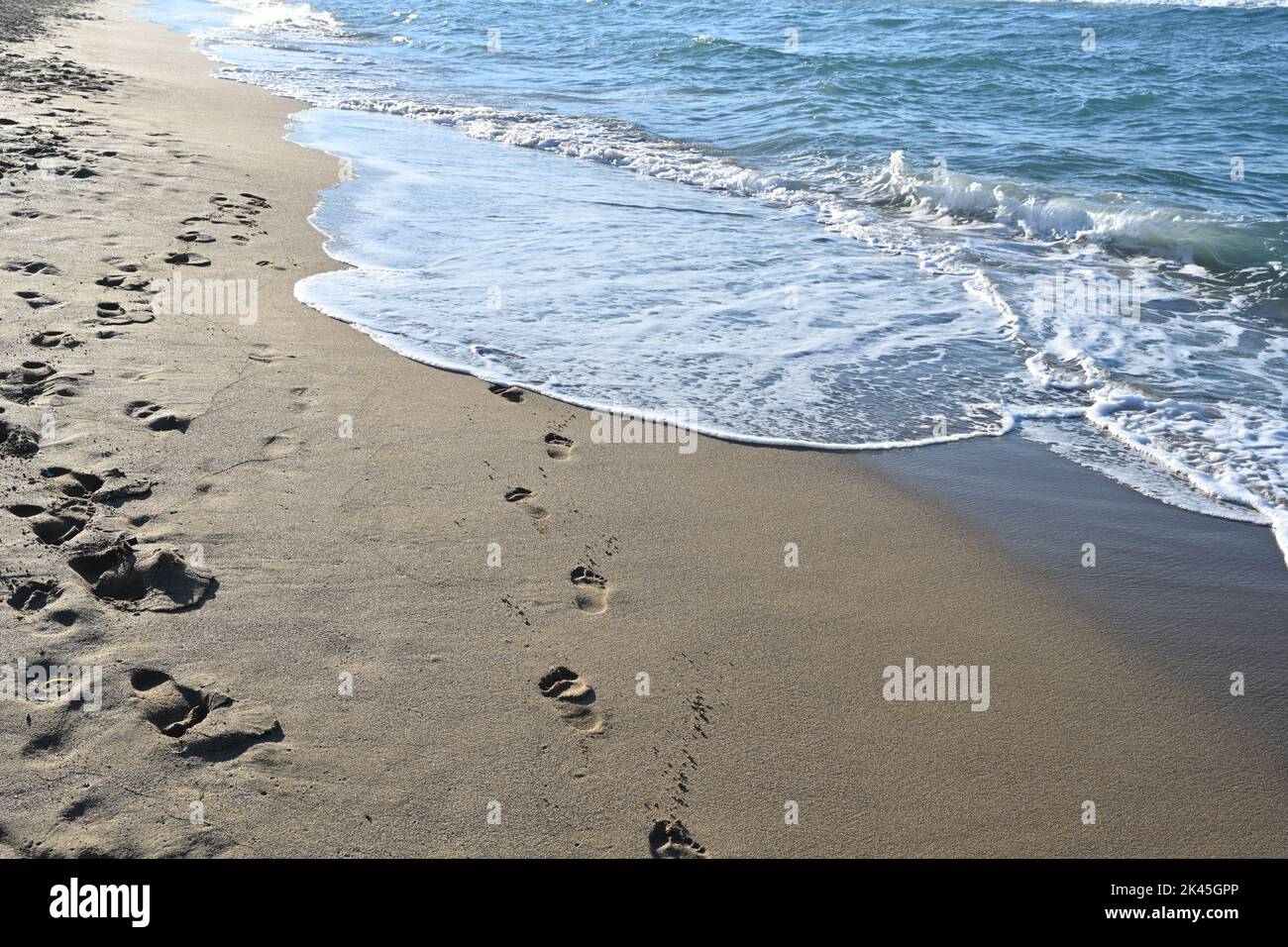 Sandy beach with footprints in the wet sand Stock Photo - Alamy