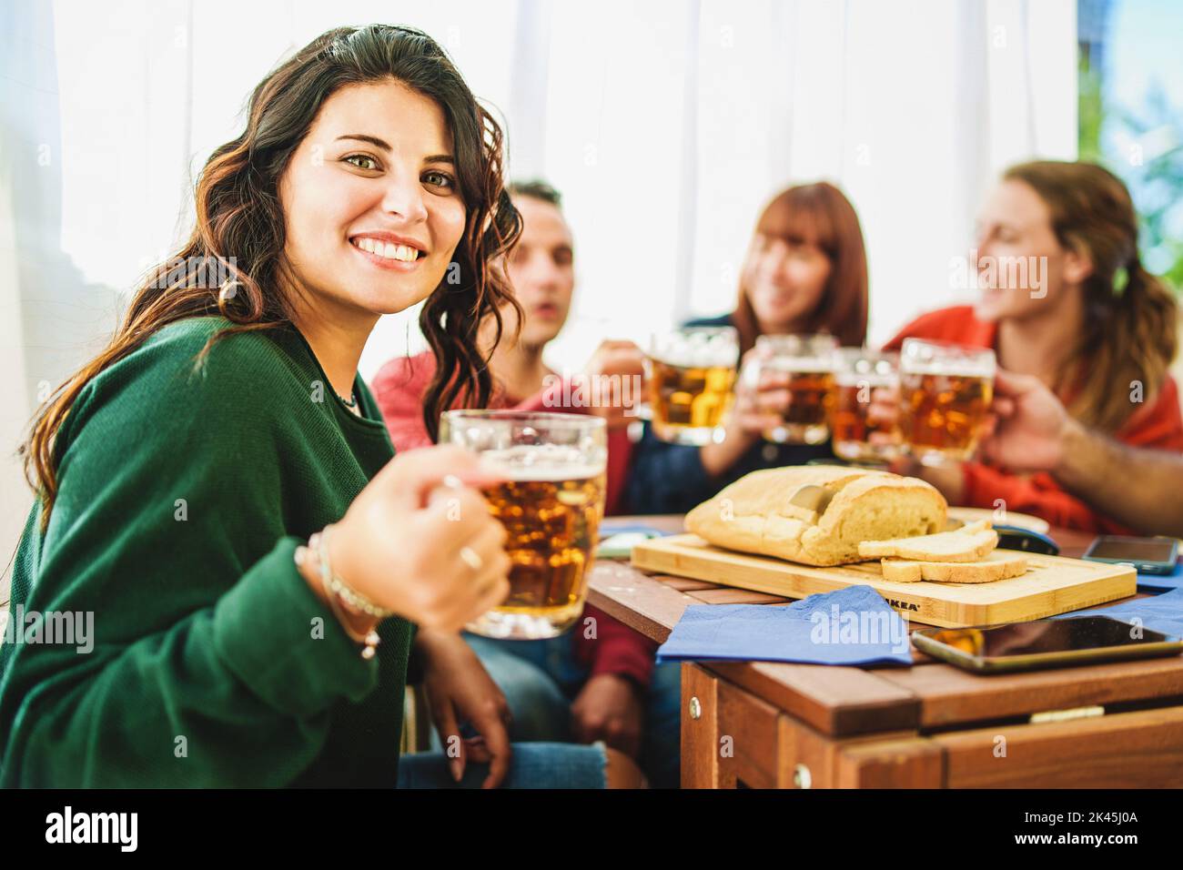 Young woman looking at the camera celebrating with beers and friends ...