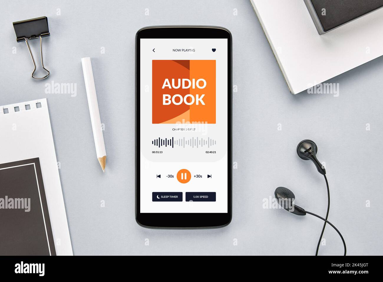 Overhead view of smartphone screen with audio book app open on desk ...