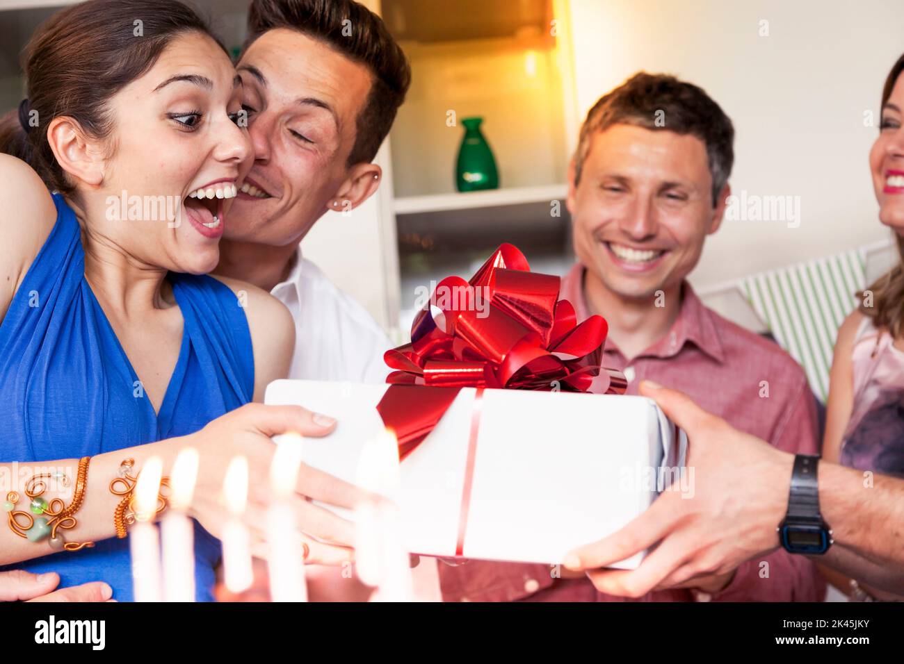 pretty girl with birthday cake receiving the gift from his friends ...