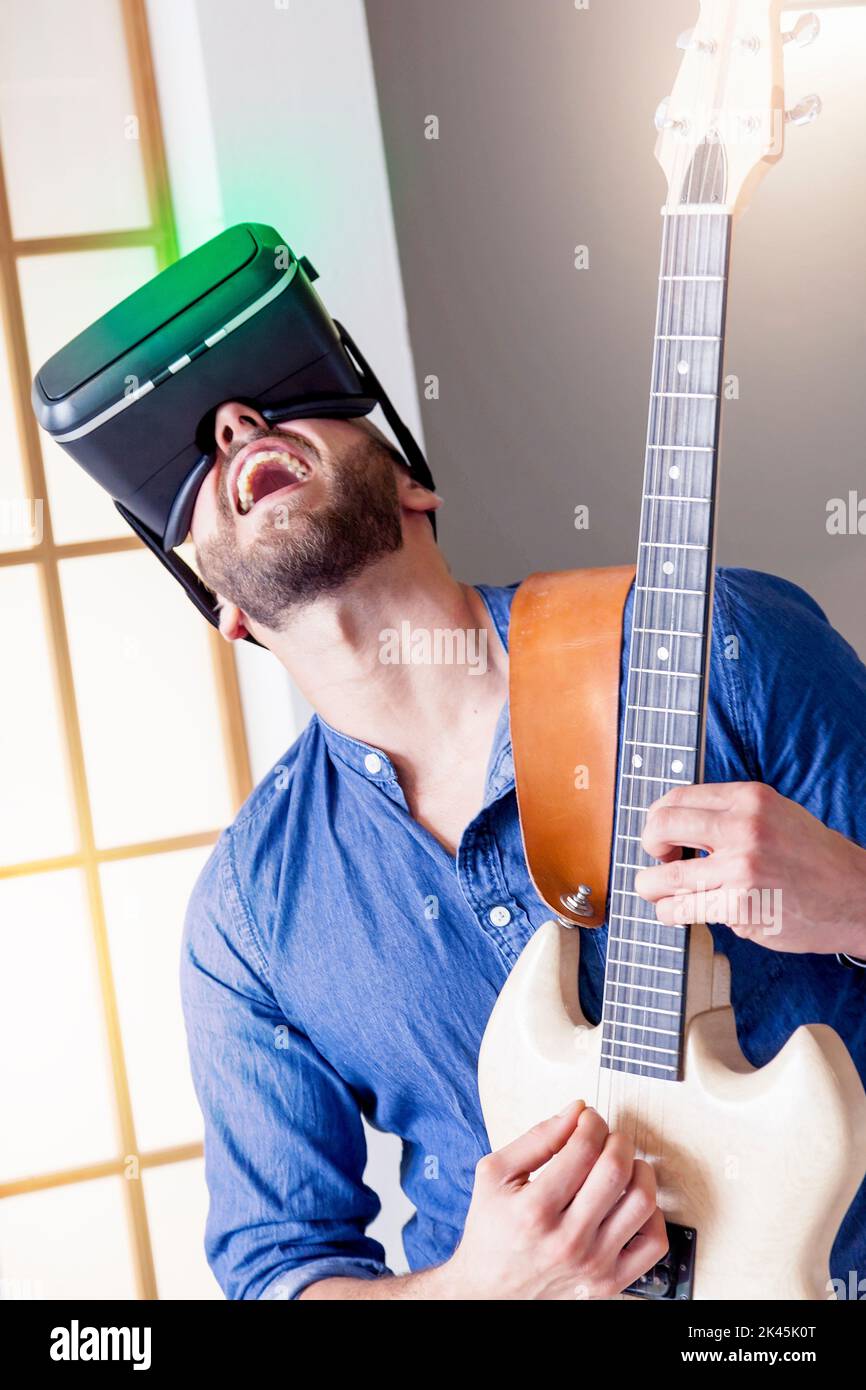young adult playing guitar at home using viewer for virtual reality ...