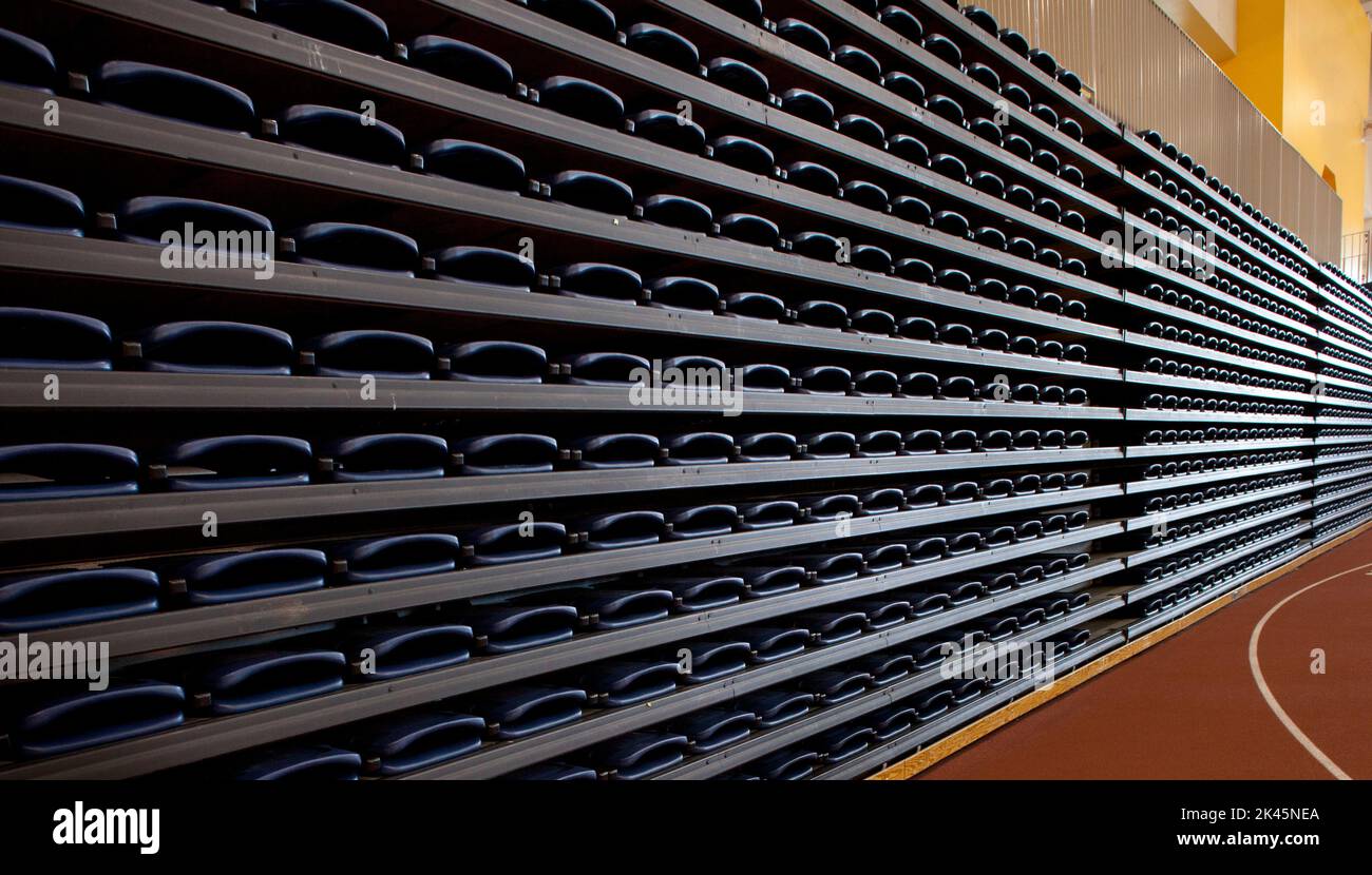 A row of folded seats,in an indoor sports venue. Stacked up and folded ...