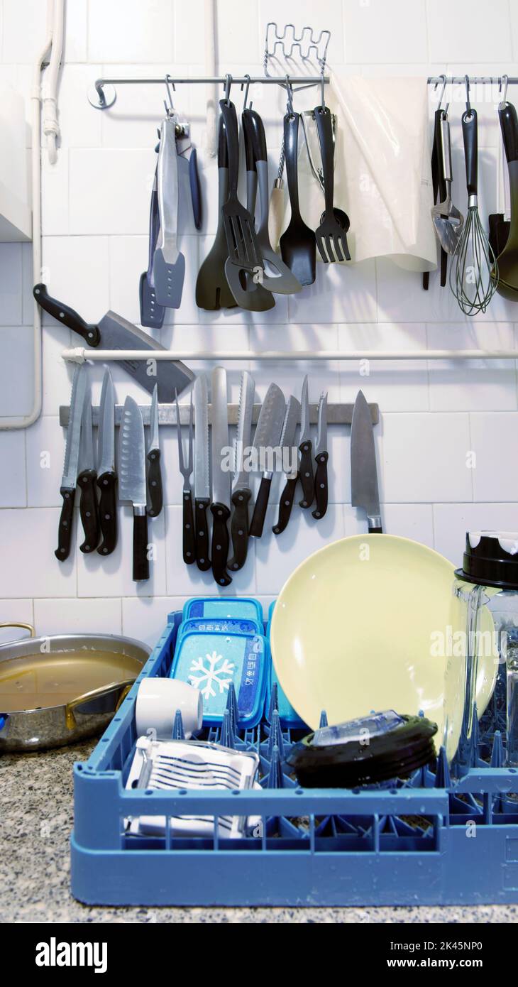 A kitchen with dishes in a rack and hanging storage of knives and ...