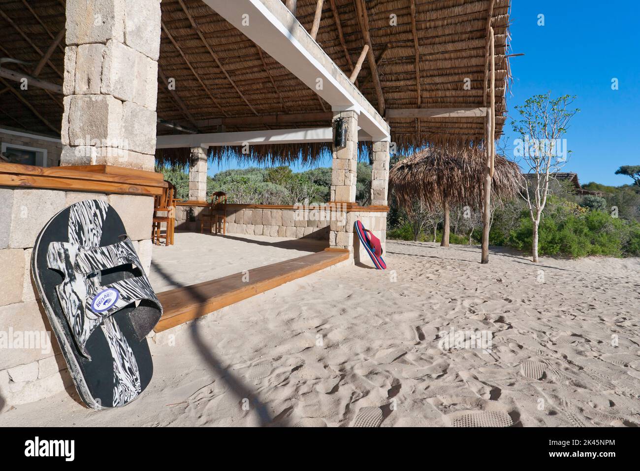 A beach resort building on a white sand beach, a pair of flipflops on ...