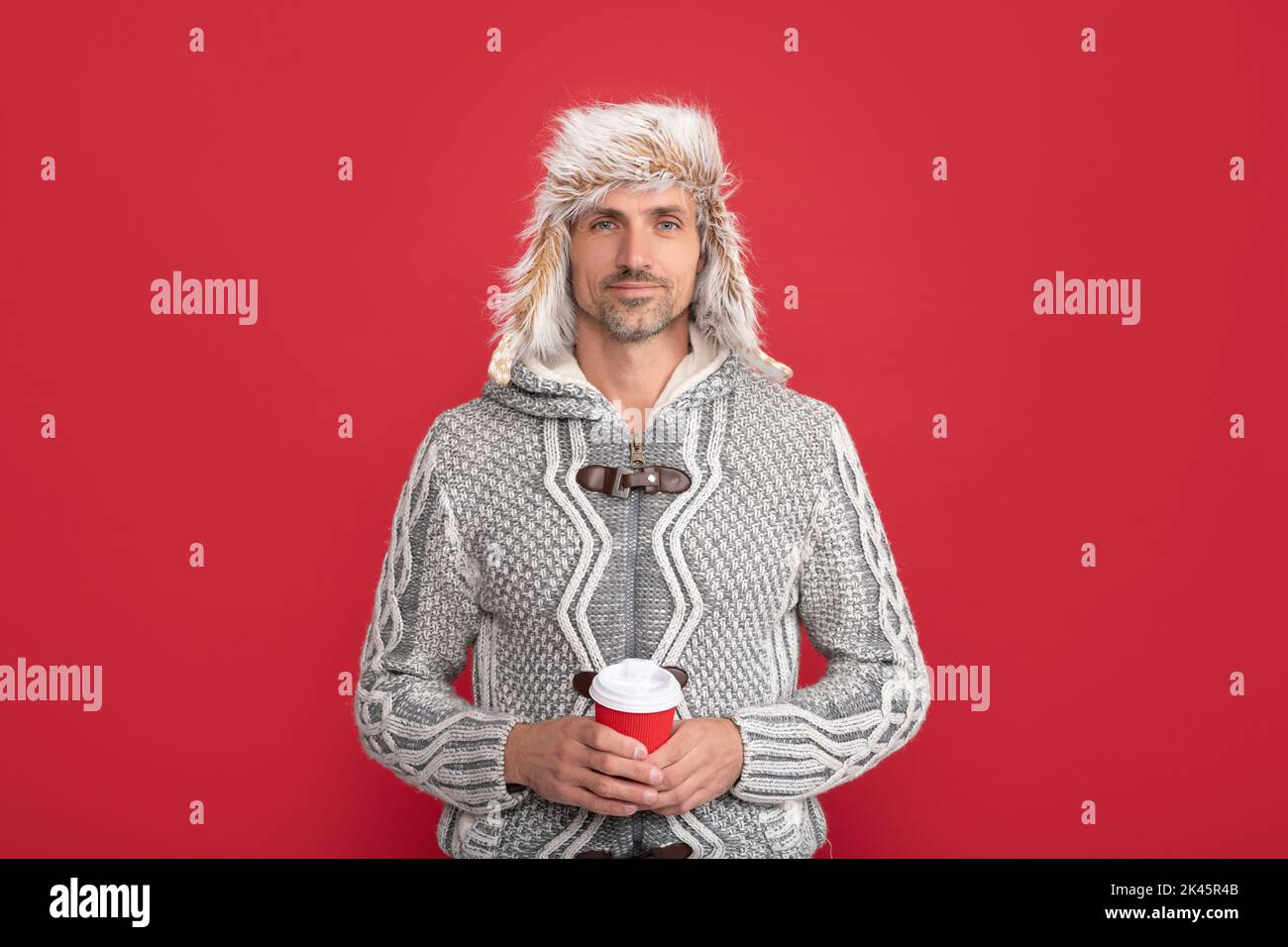 morning coffee in take away cup. grizzled guy in sweater and hat on red ...