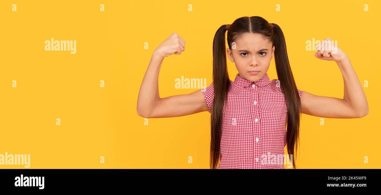 Serious girl child show strength gesture flexing arms yellow background ...