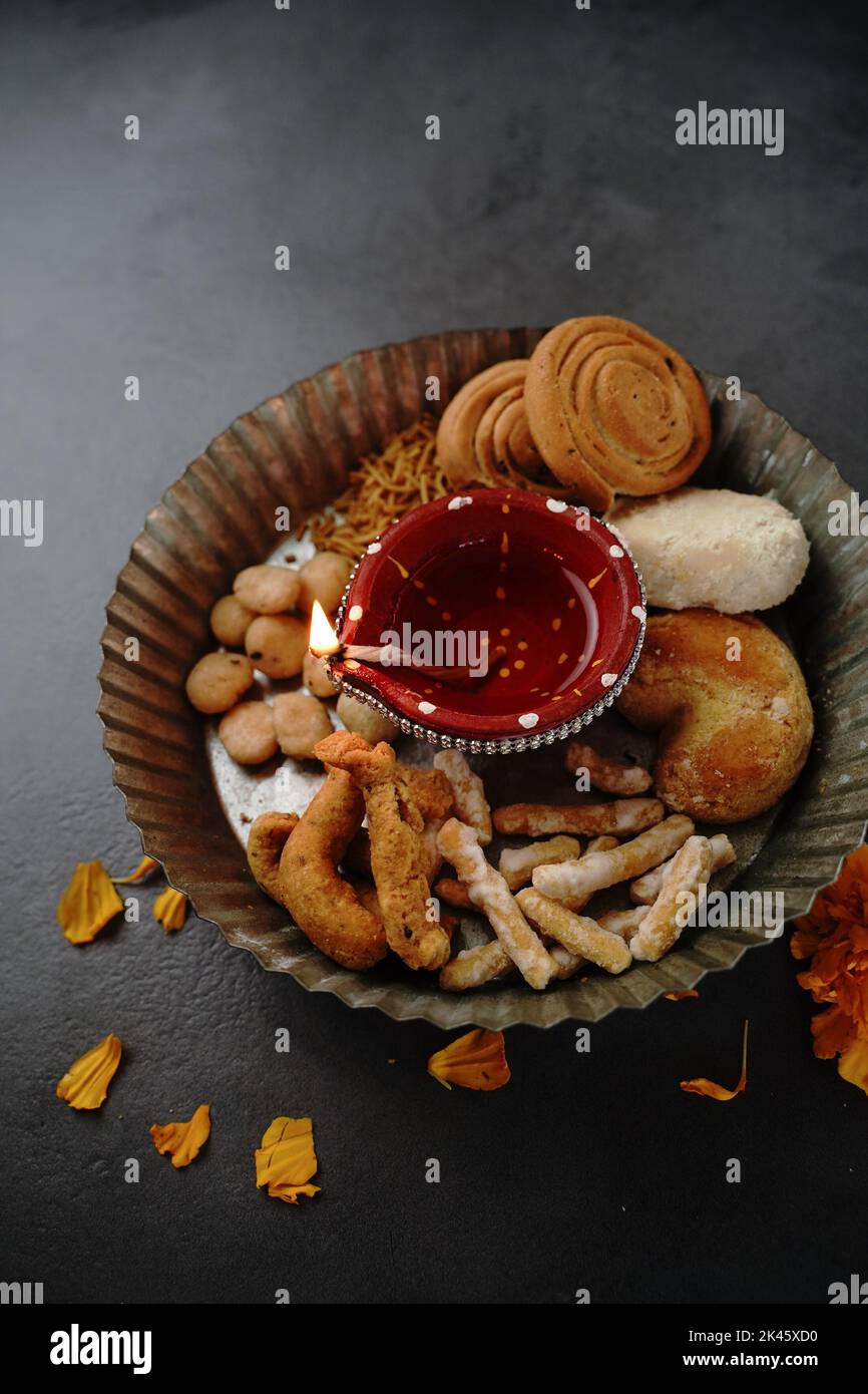 Diwali snacks with Diya lamp lit - Deepavali background, selective focu ...